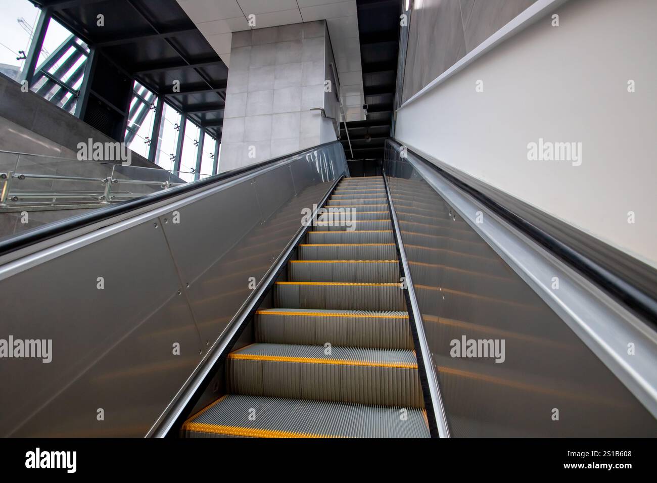 There is an escalator featuring yellow steps that move in both upward ...