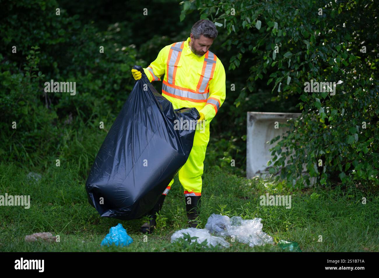 Environment plastic pollution. Volunteer collecting trash in the forest and holding a garbage ...
