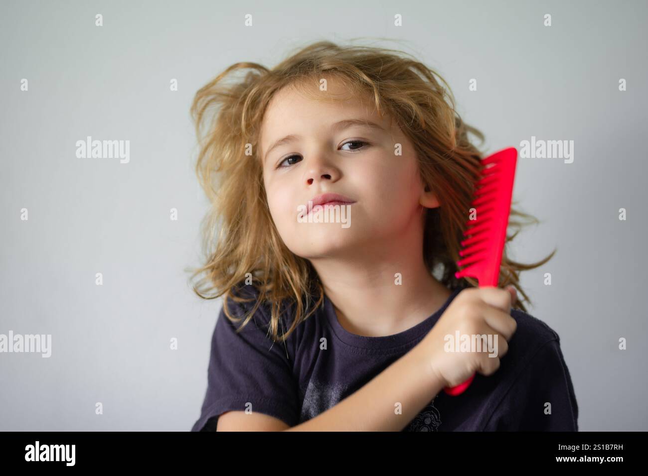 Closeup portrait of little child brushing hair isolated on gray studio ...