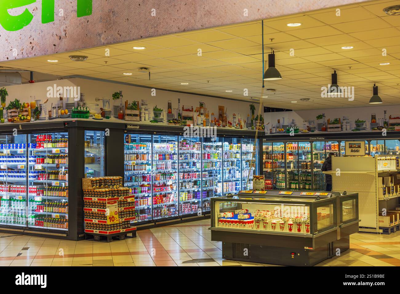 Refrigerated display cases in supermarket filled with beverages, dairy ...