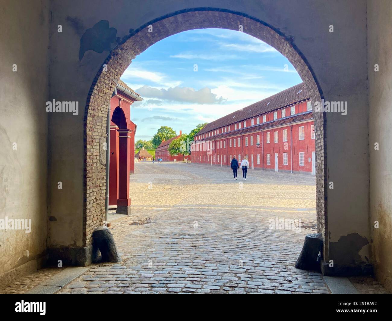 View Through a Brick Archway Framing Red Barracks, Cobblestone Path ...