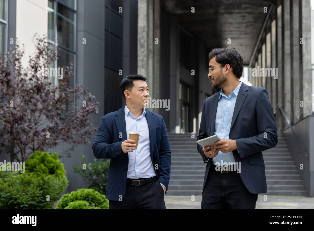 Two business colleagues walking down the street outside an office ...
