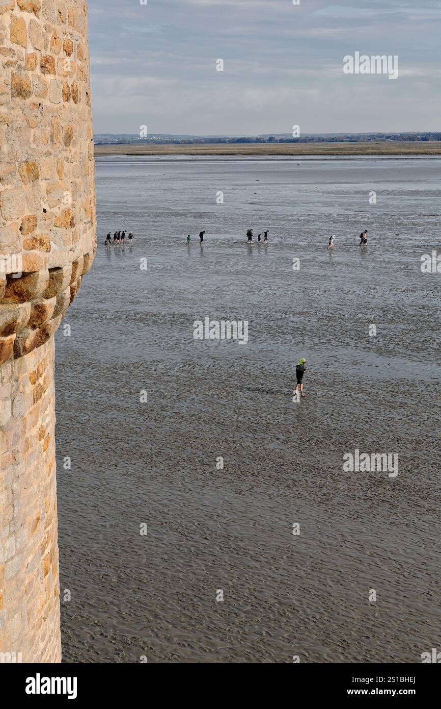 154 Mont-Saint-Michel. Visitors walk the surrounding mudflats, seen ...