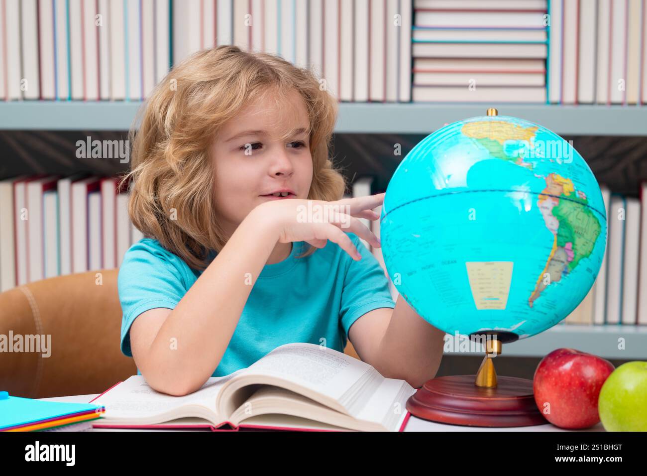 School pupil looking at globe in library, geography lesson. School ...