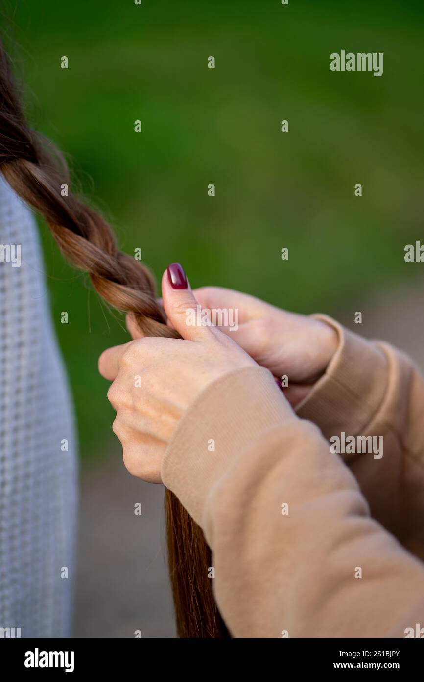 View of female hands weaving a braid from long female hair Stock Photo ...