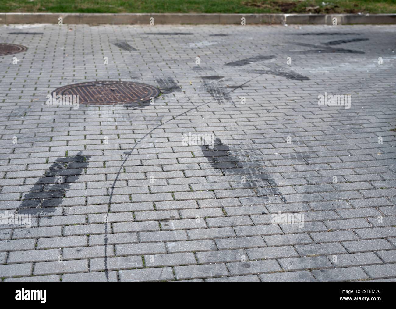 photo A paved surface featuring tire marks and manhole covers ...