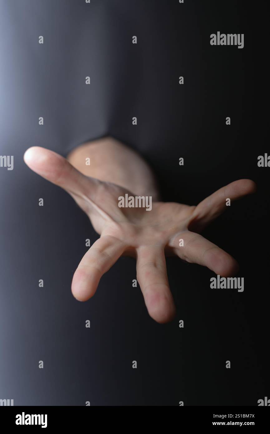 photo Open hand reaching outward in dramatic gesture against black ...