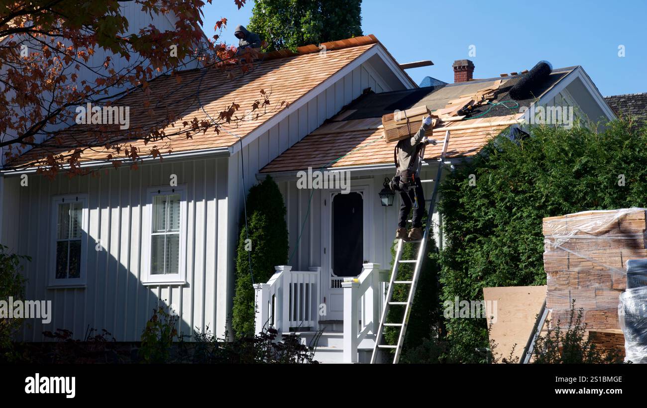 Construction workers fixing roof against blue sky, install shingles at ...