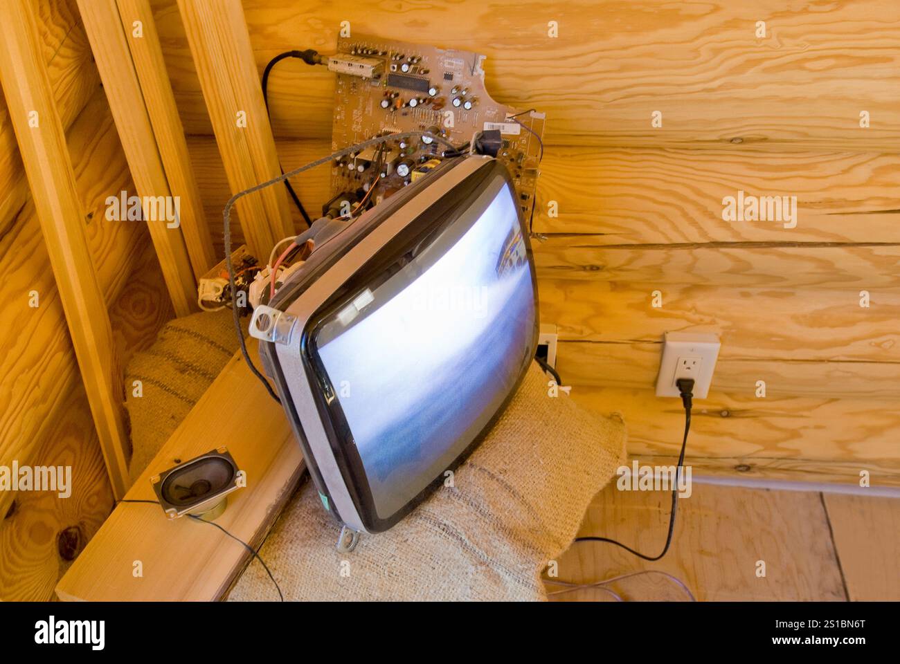 a disassembled working TV set sitting in a corner of a log cabin ...