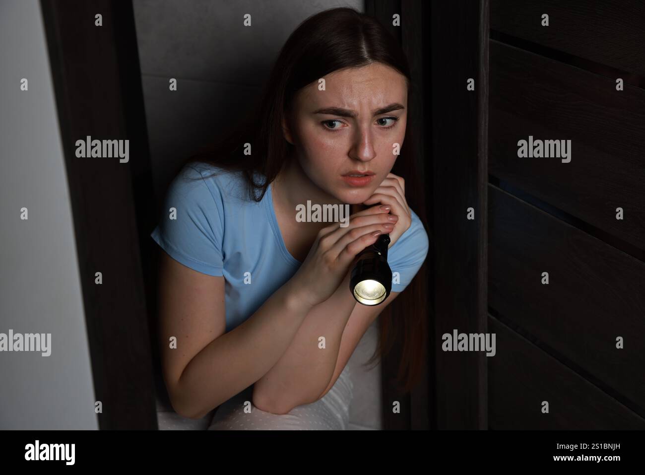 Fear of darkness. Scared young woman with flashlight indoors at night ...