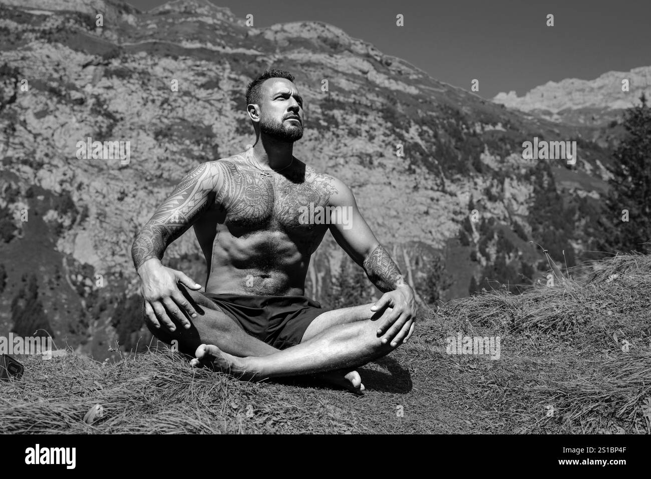Latin Man meditating in lotus pose in grass outdoors. Sportsman doing ...