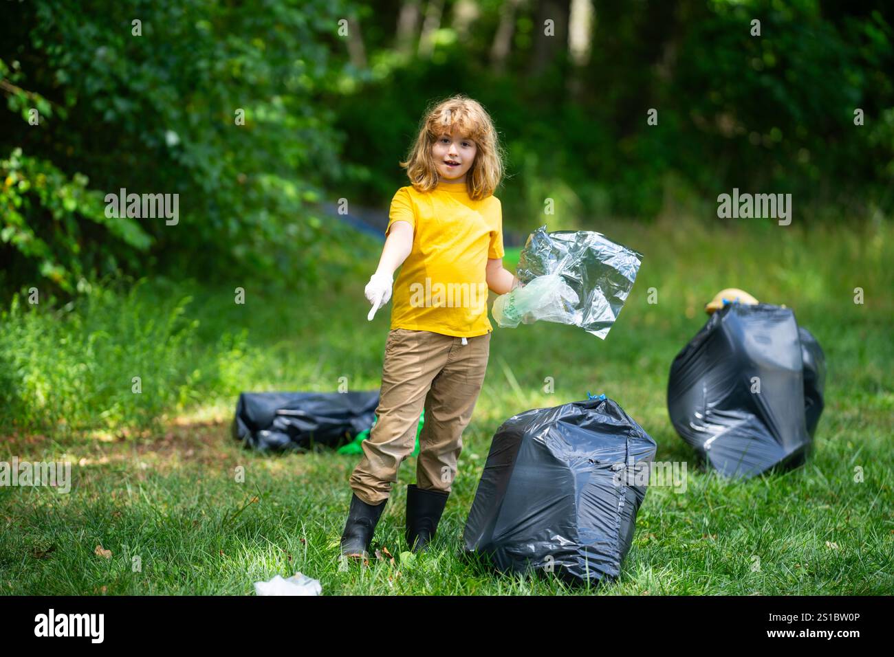 Kid in rubber gloves with trash bag clean up garbage on forest outdoor ...