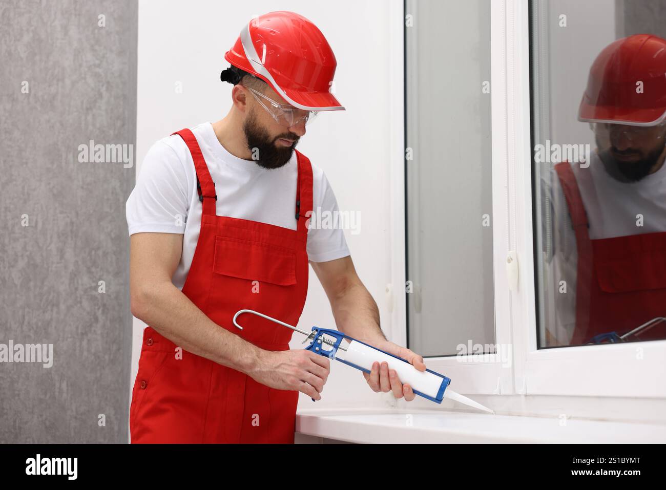 Worker with caulking gun sealing window indoors Stock Photo - Alamy