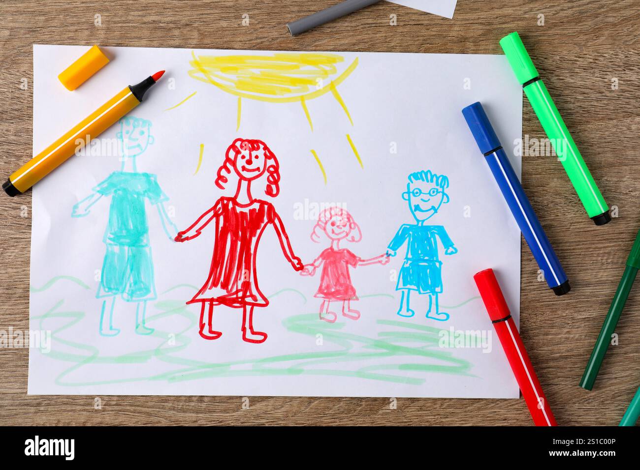Child's drawing of happy family and felt tip pens on wooden table, top ...