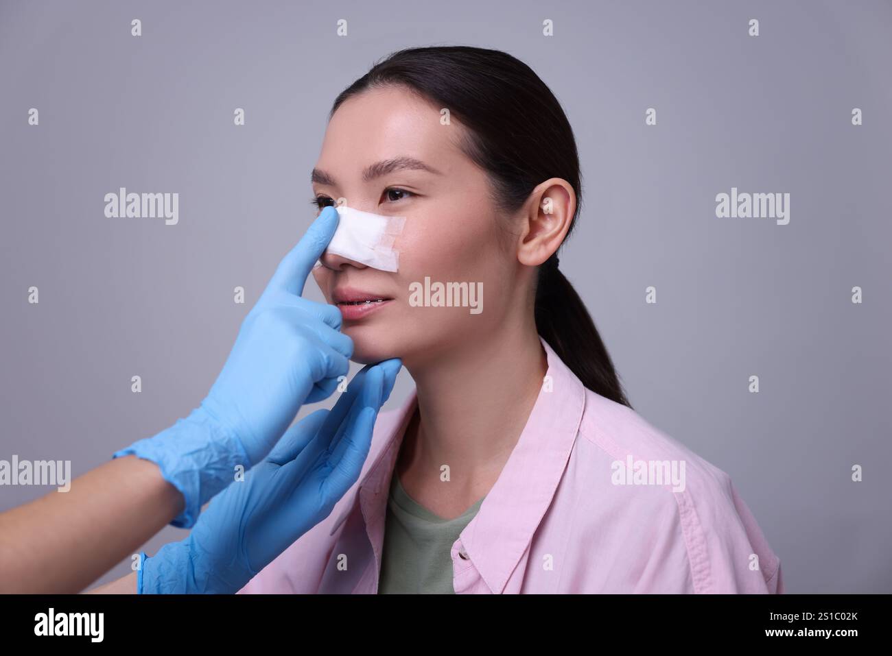 Doctor checking patient's nose after plastic surgery operation on light ...