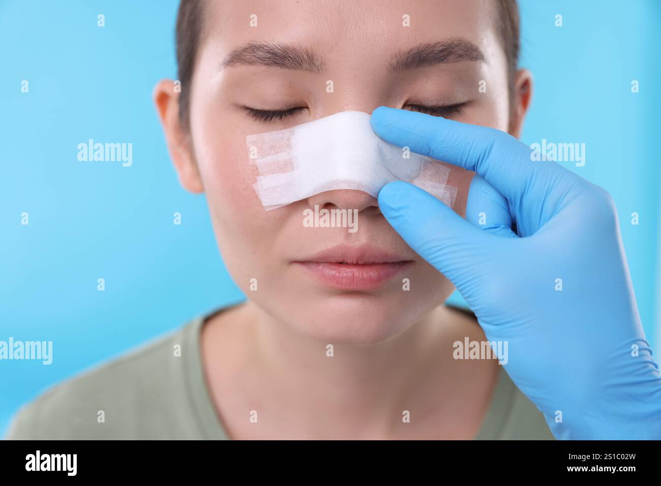 Doctor checking patient's nose after plastic surgery operation on light ...