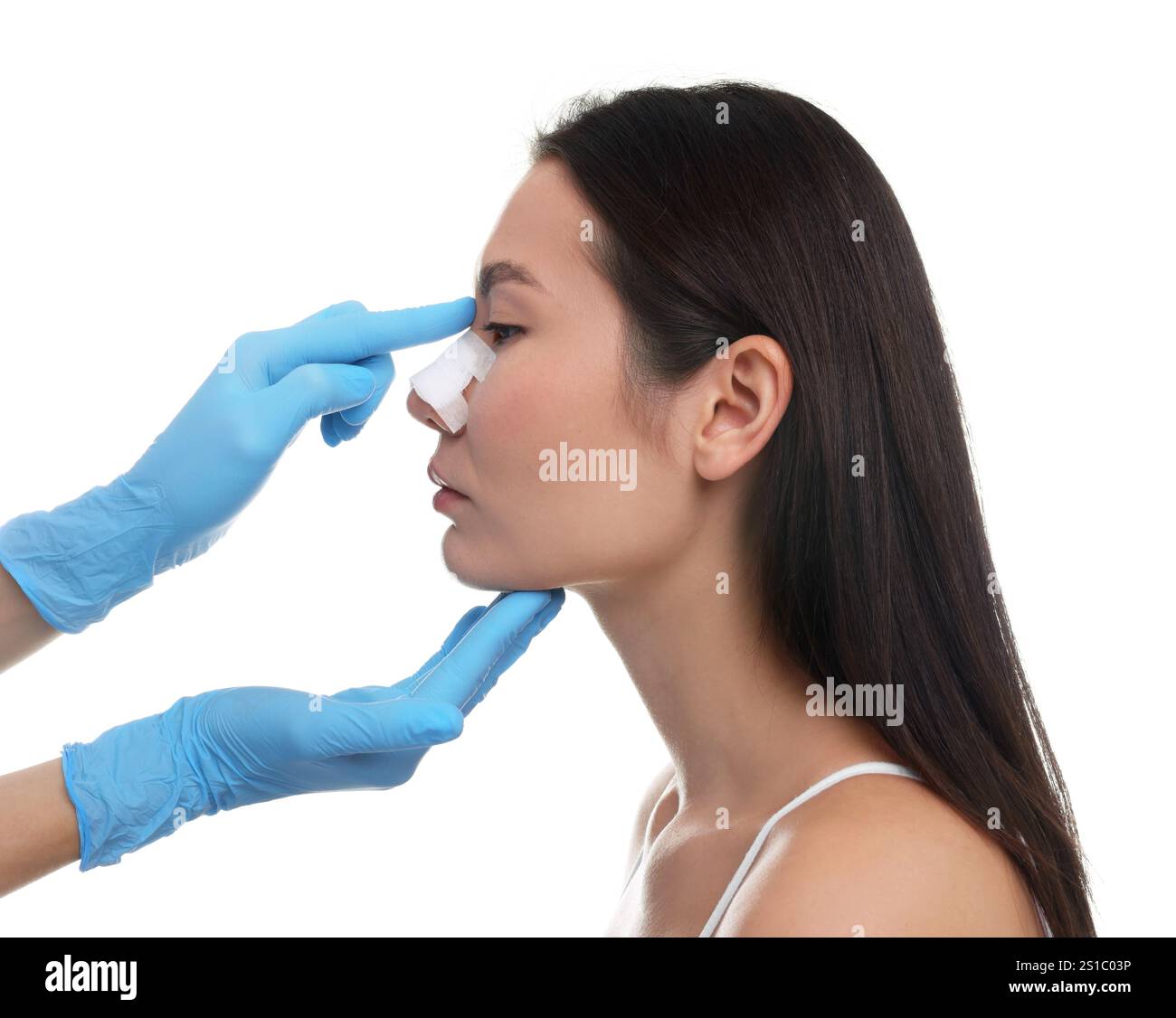 Doctor checking patient's nose after plastic surgery operation on white ...