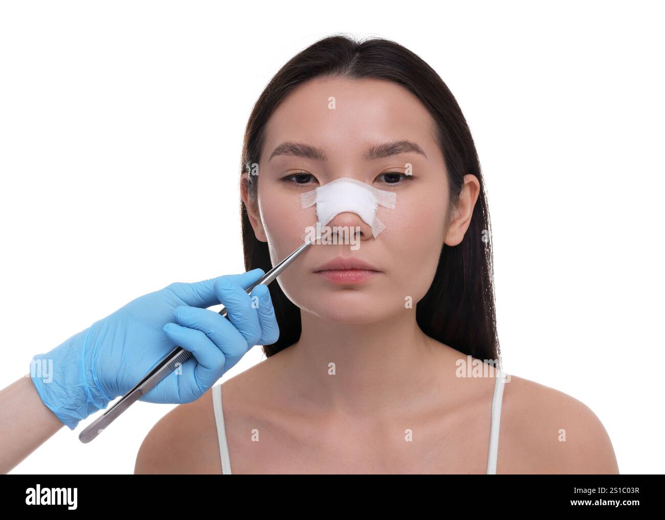 Doctor removing medical bandage from patient's nose after plastic surgery operation on white ...