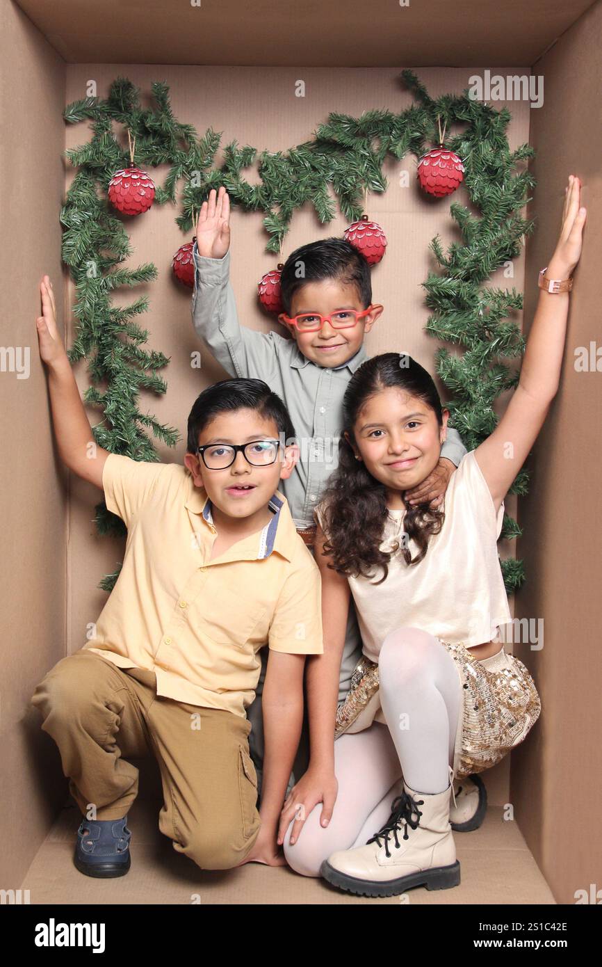 Two dark-skinned Latino brothers and sister inside a decorated ...