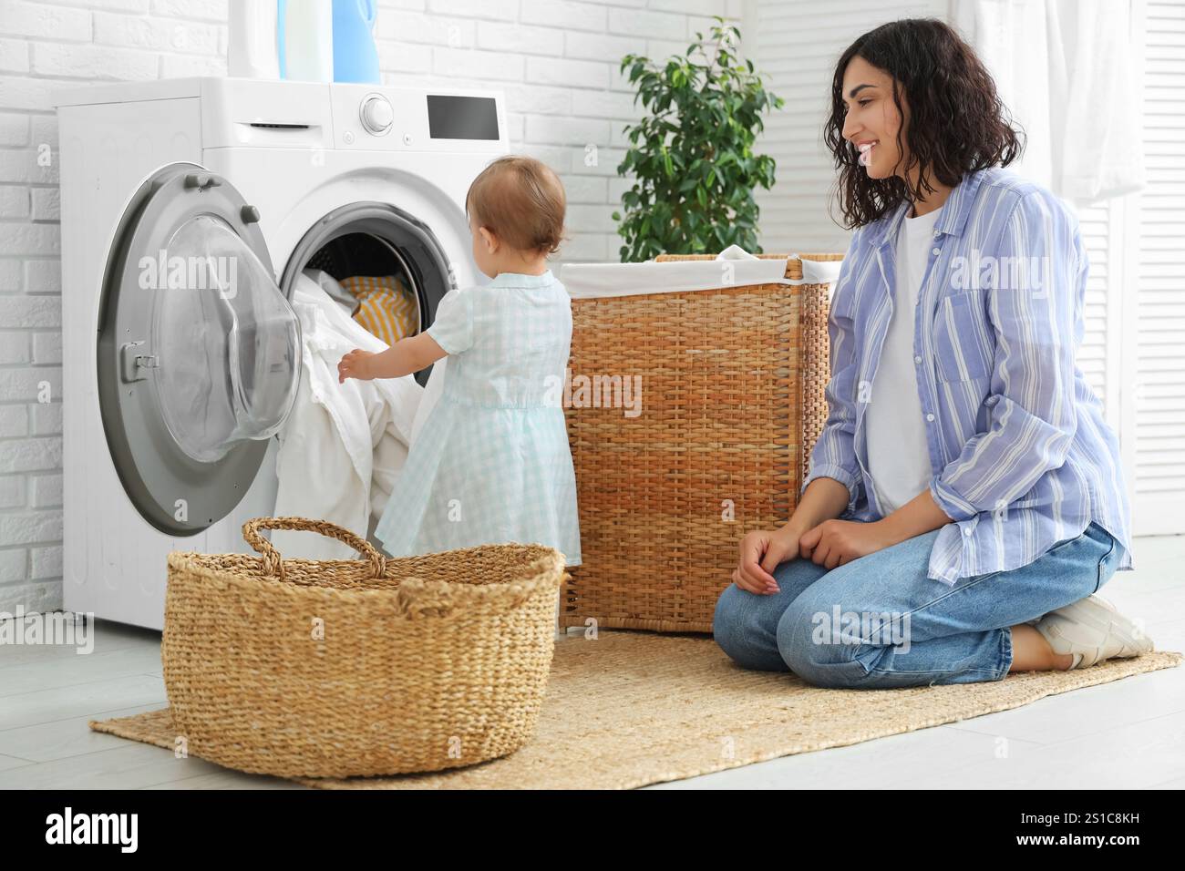 Cute little baby helping her mother with laundry in bathroom Stock ...