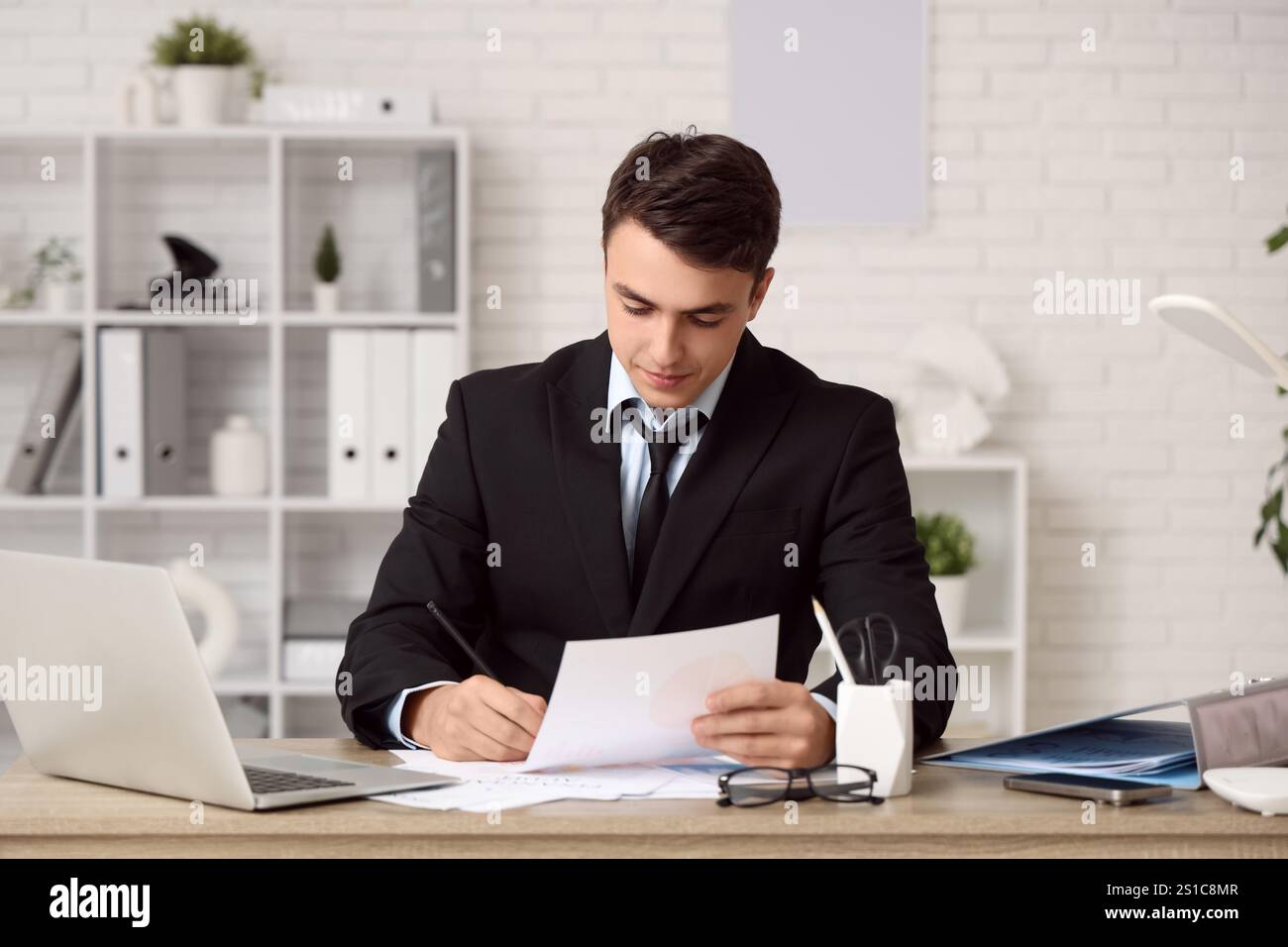 Male economist working with diagrams at table in office Stock Photo - Alamy