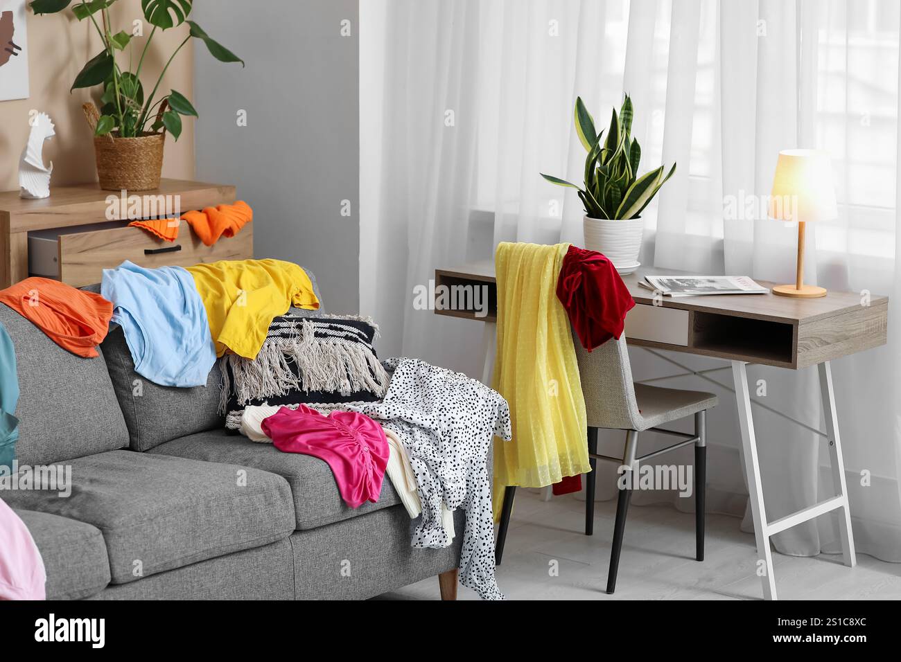 Interior of messy living room with grey sofa and piles of different ...