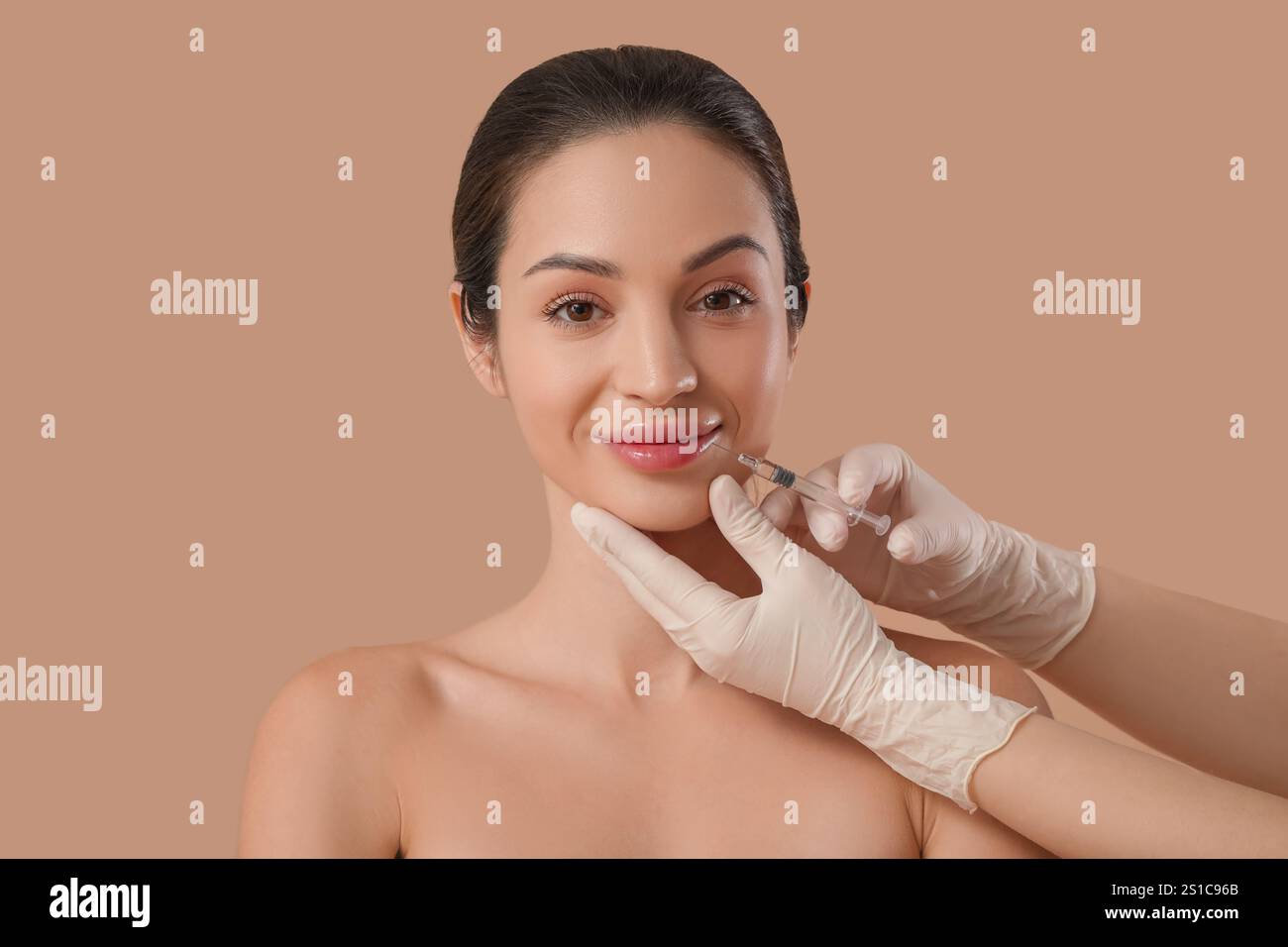 Beautiful young happy woman receiving lips injection on beige ...
