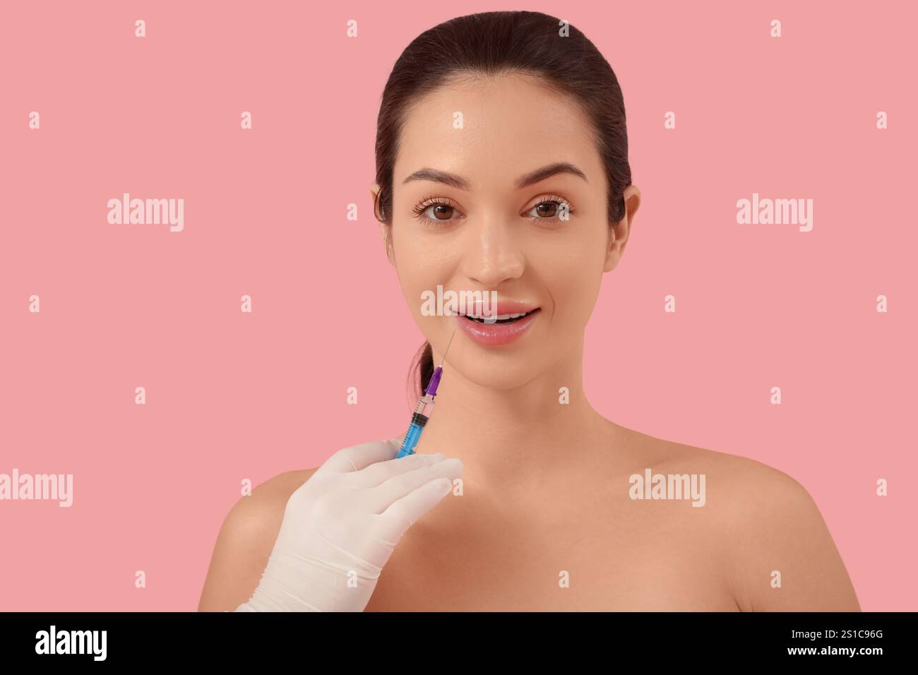 Beautiful young happy woman receiving lips injection on pink background ...