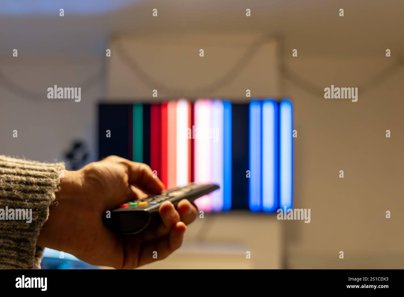 Hand holding remote control changing channels on television displaying ...