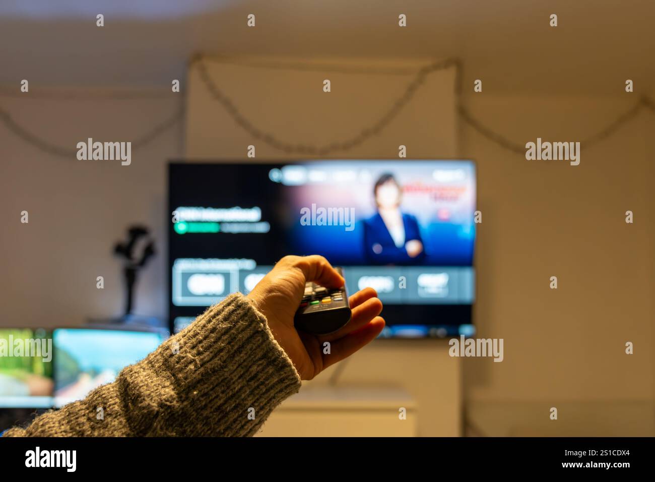 Hand holding remote control, pointing at television, changing channels ...