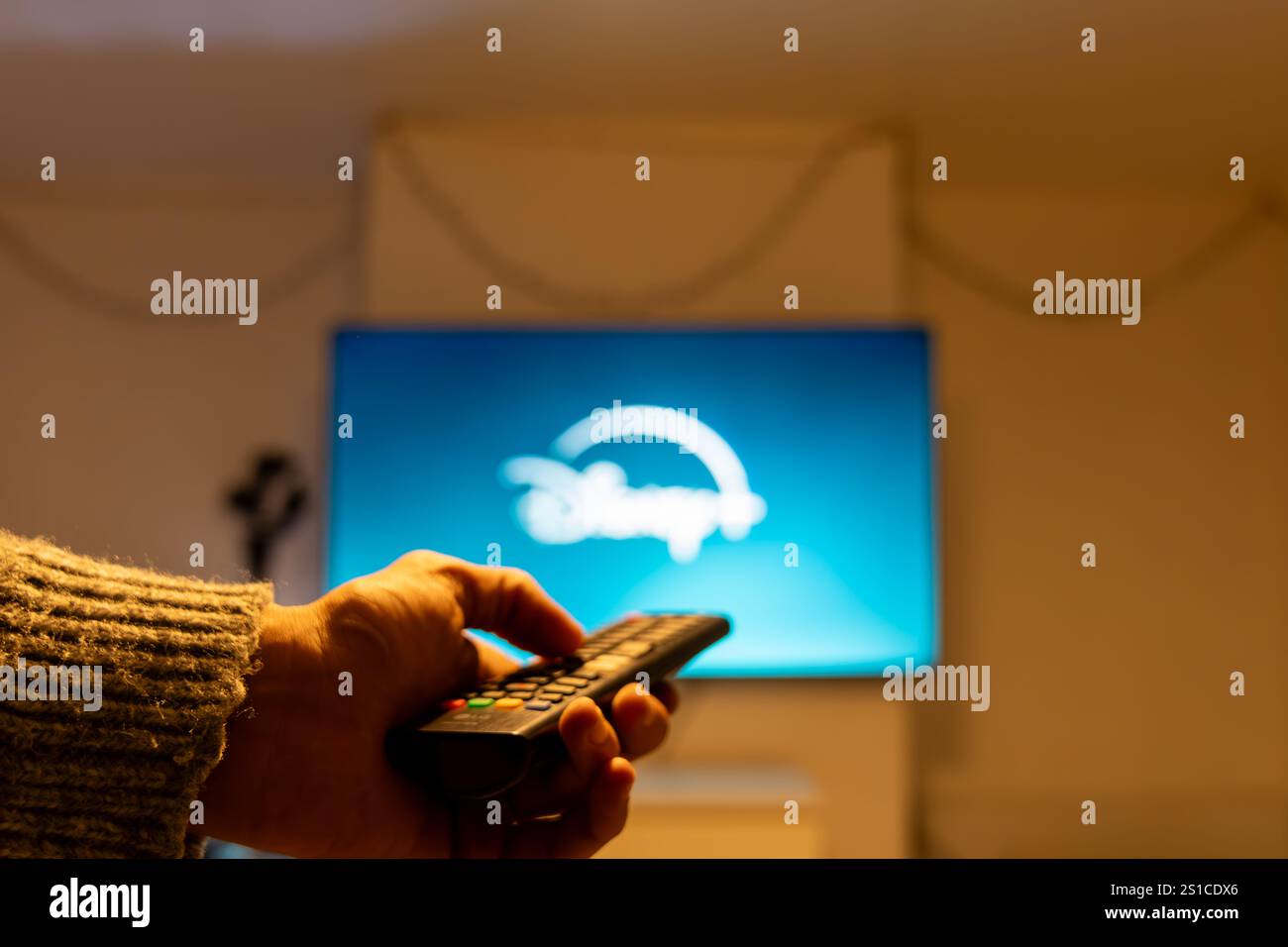 Hand holding remote control, pointing at TV screen showing streaming ...
