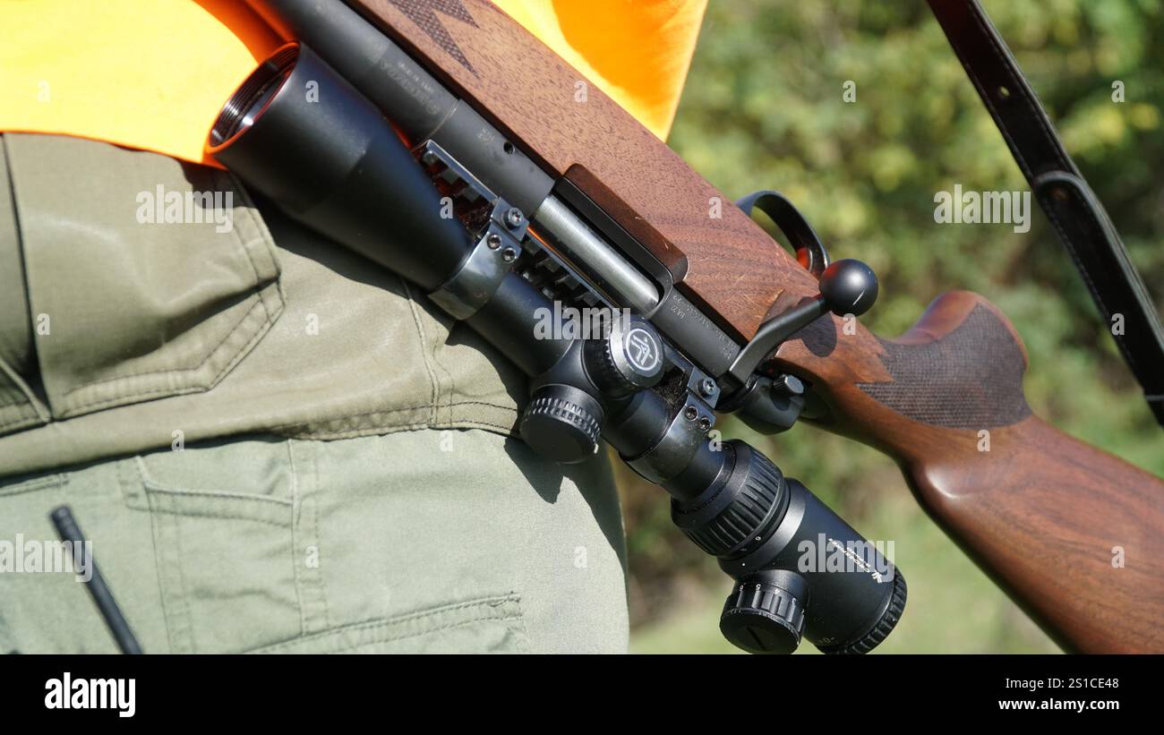 A close-up of a hunter carrying a rifle with a mounted scope ...