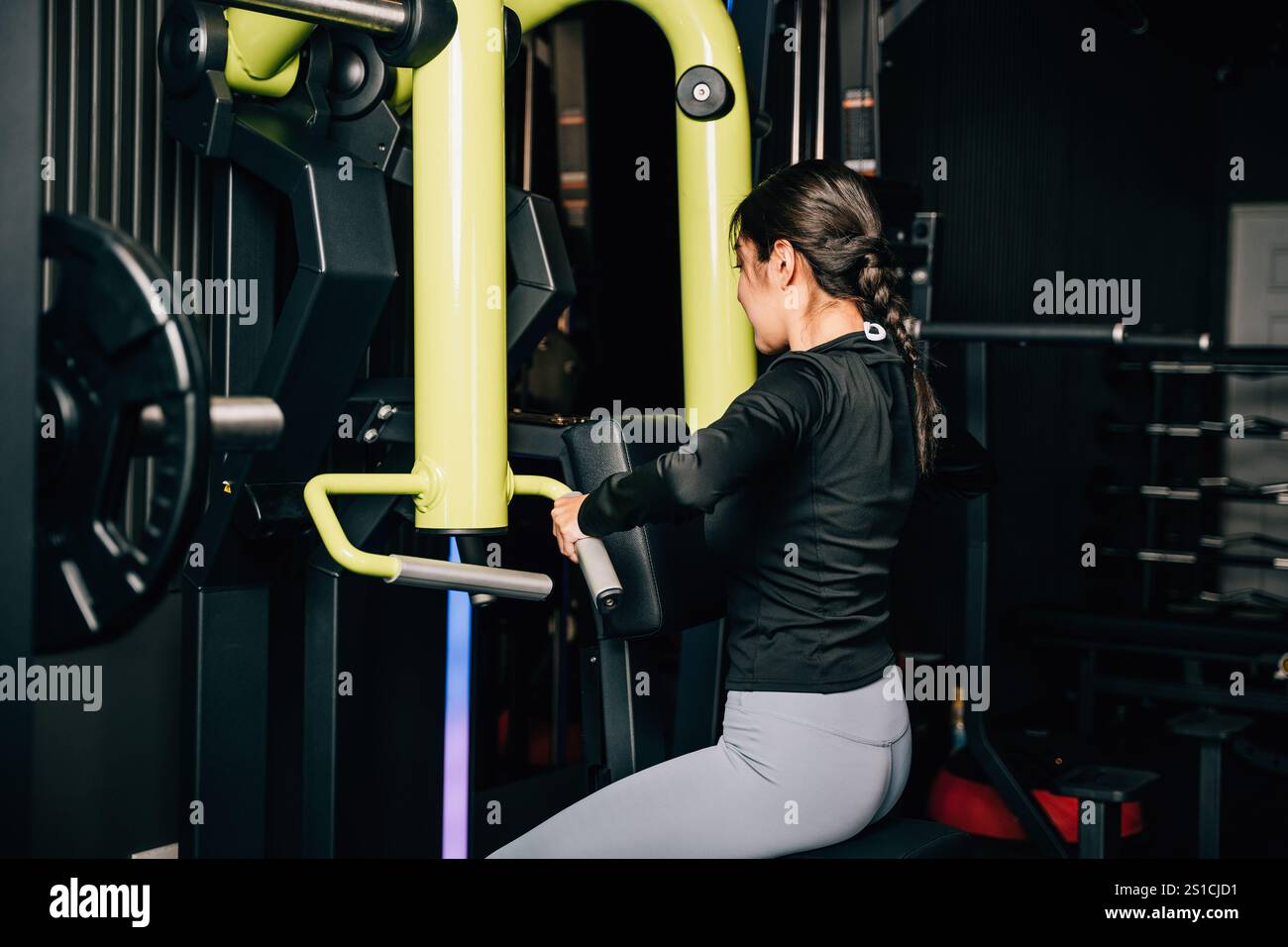 Portrait of beautiful Asian young woman performing squats on a gym ...
