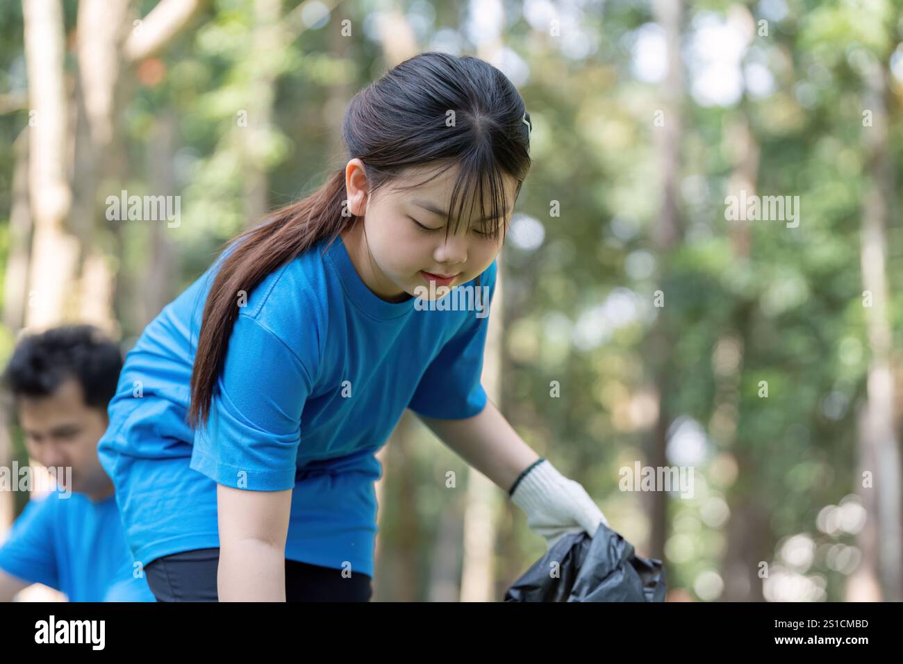 Family volunteers collecting garbage in nature community clean up event ...