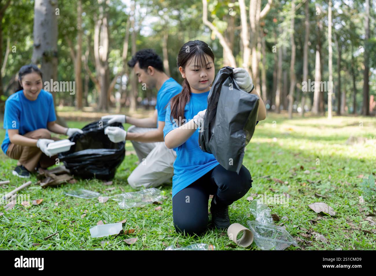 Family volunteers collecting garbage in a park community clean up event ...