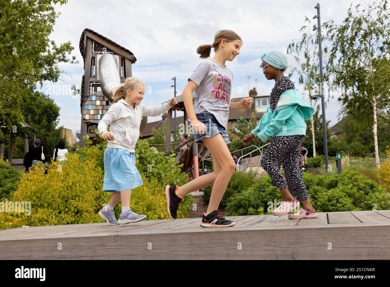 Three children play on a walk-on see-saw in a playground at Brent Cross Town, a development in ...