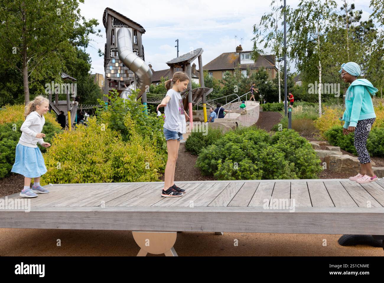 Three children play on a walk-on see-saw in a playground at Brent Cross ...