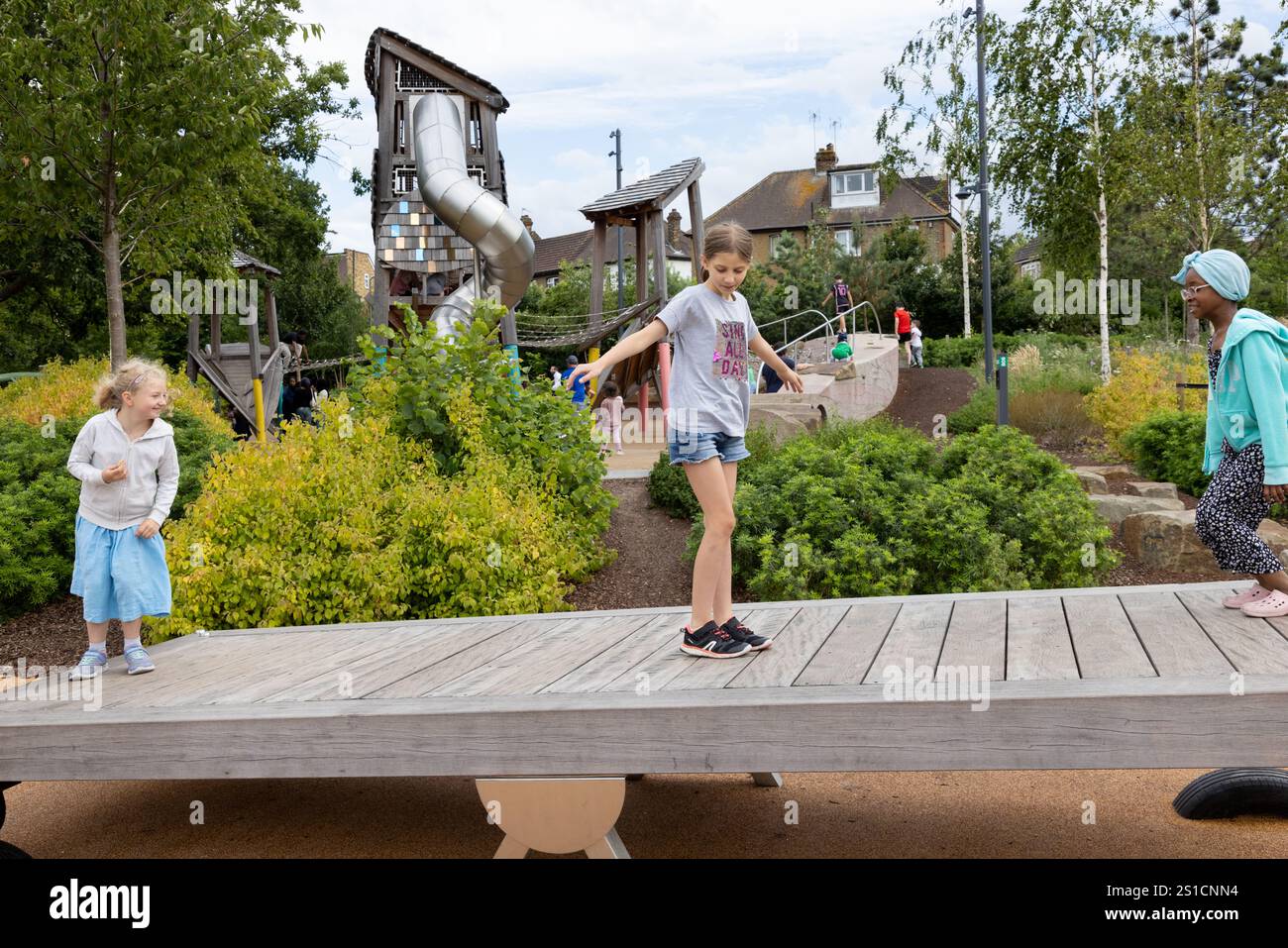 Three children play on a walk-on see-saw in a playground at Brent Cross ...