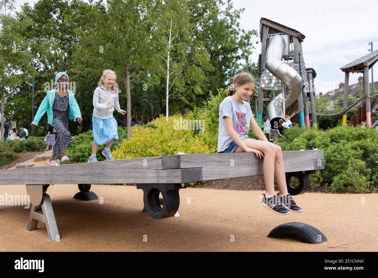 Three children play on a walk-on see-saw in a playground at Brent Cross ...