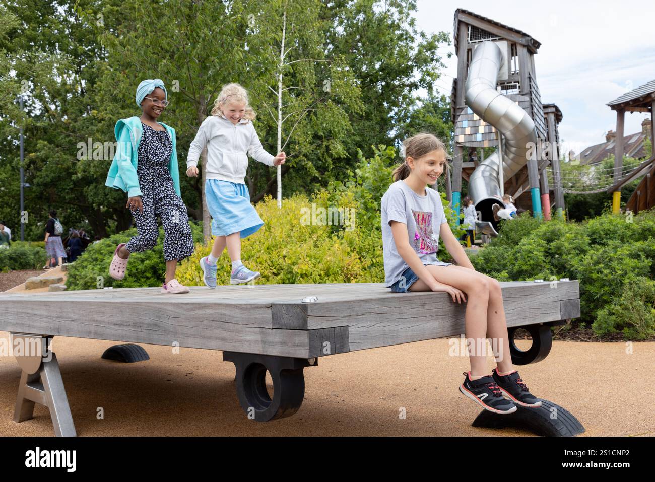 Three children play on a walk-on see-saw in a playground at Brent Cross ...