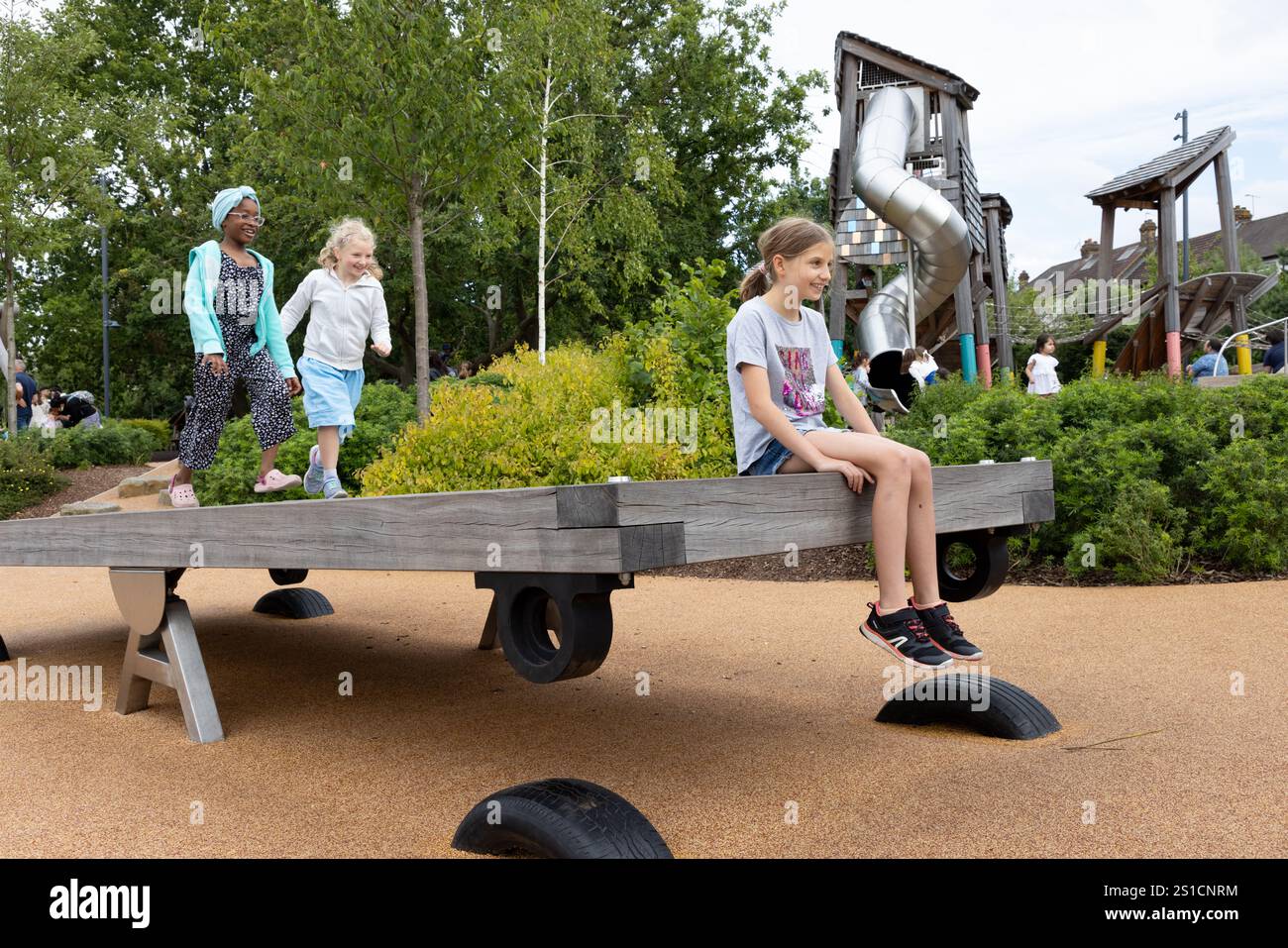 Three children play on a walk-on see-saw in a playground at Brent Cross ...
