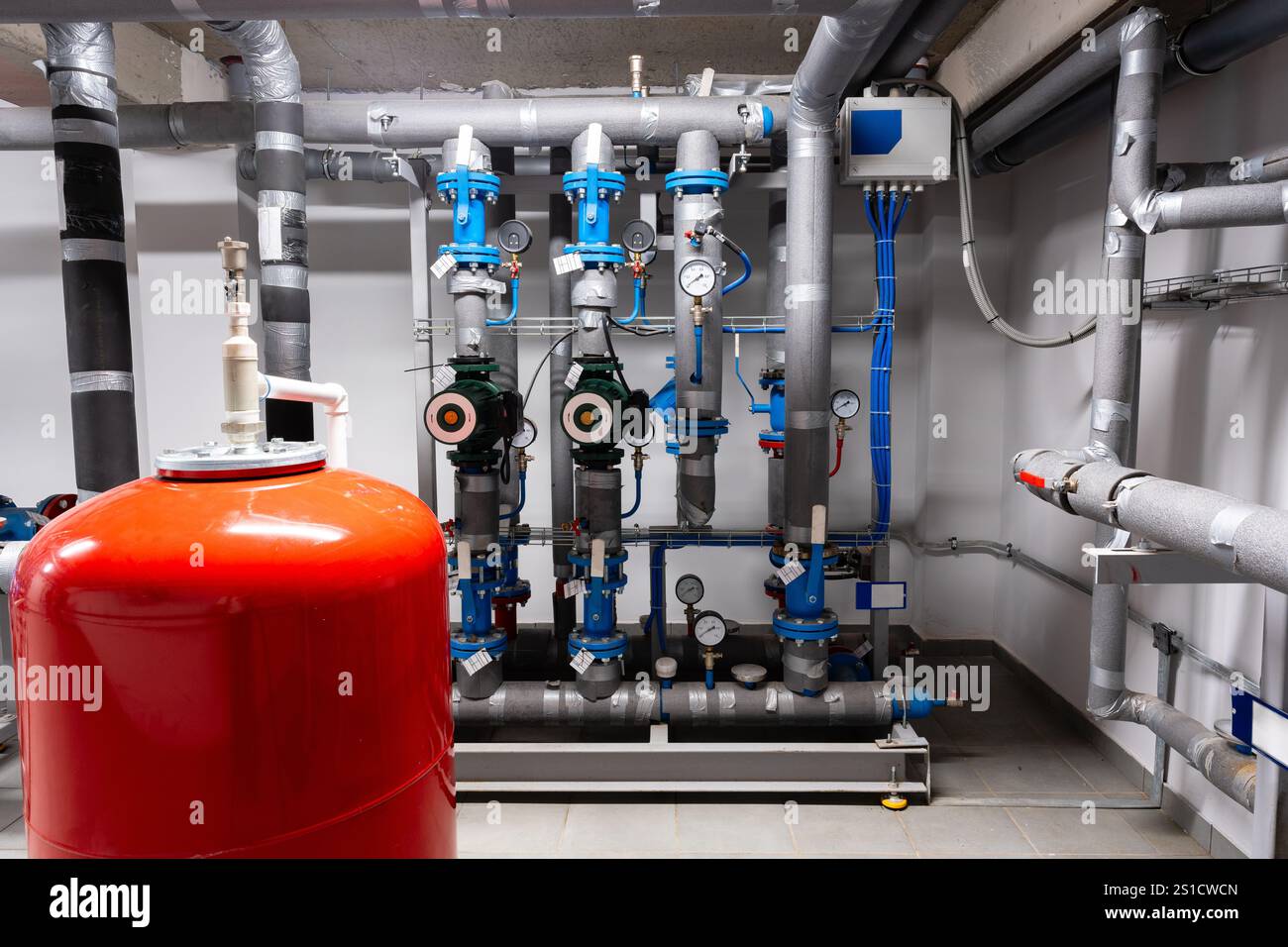Modern plumbing system with red tank and blue valves in a mechanical ...