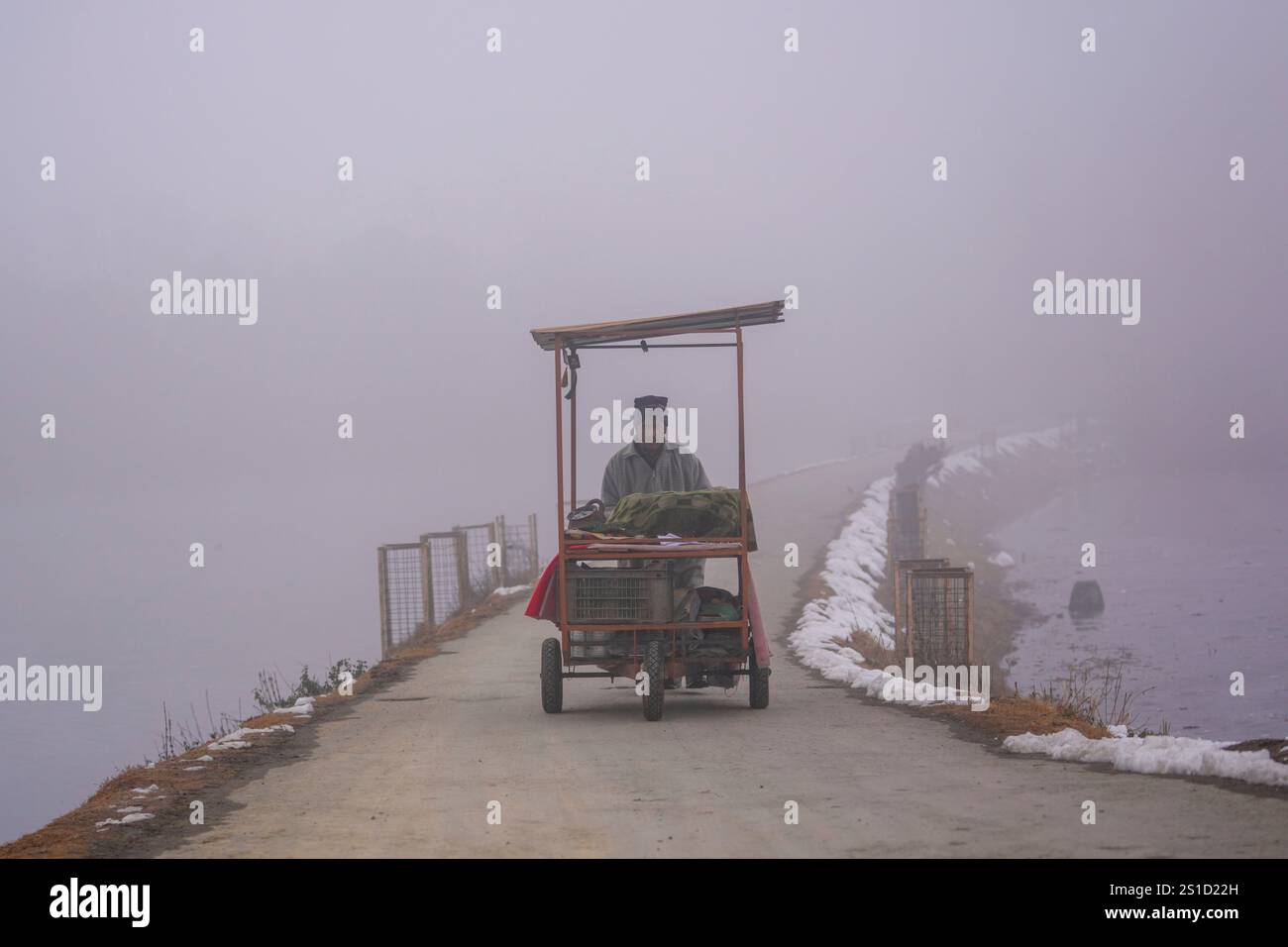 A local vendor pushes his cart on a cold and foggy morning in the ...