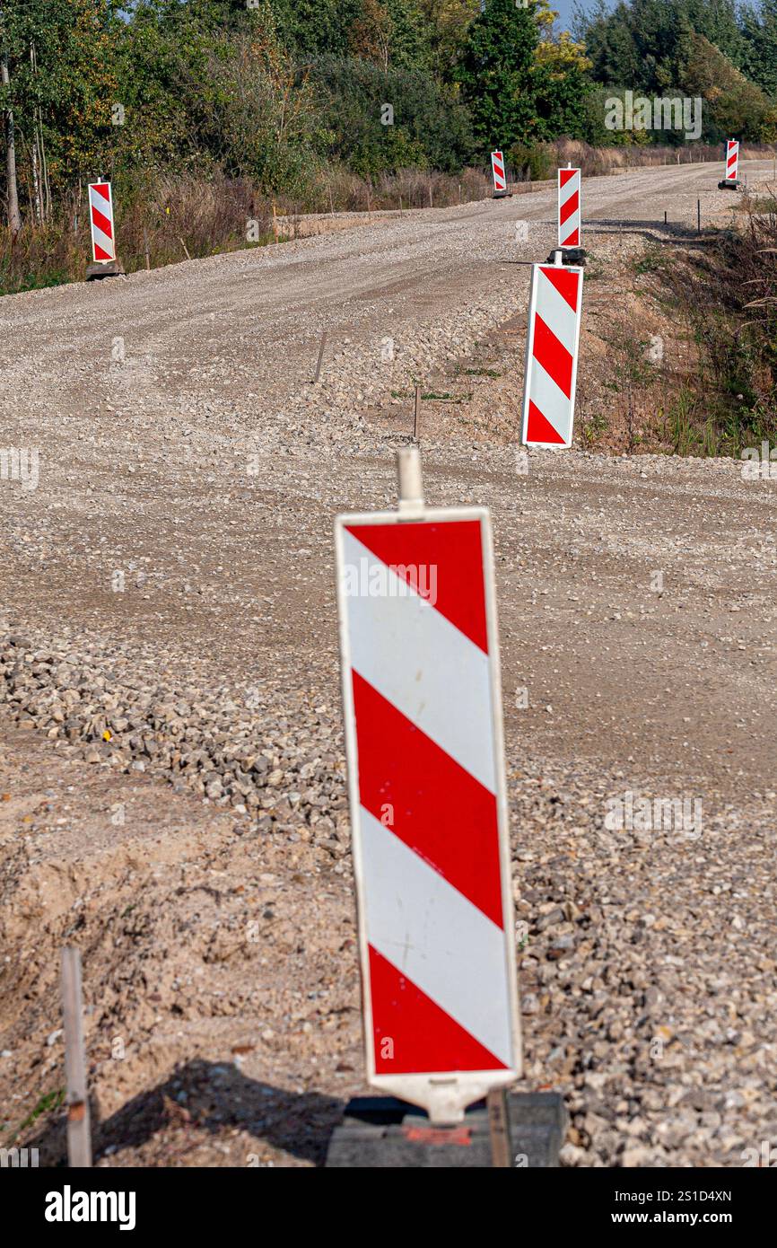 Construction site of a gravel road lined with red-and-white traffic ...