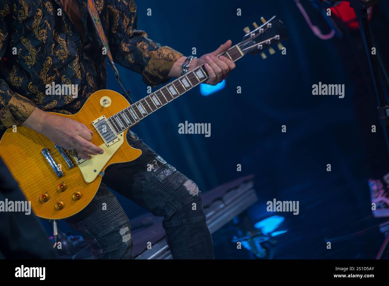 Guitarist performing on stage with electric guitar during energetic ...