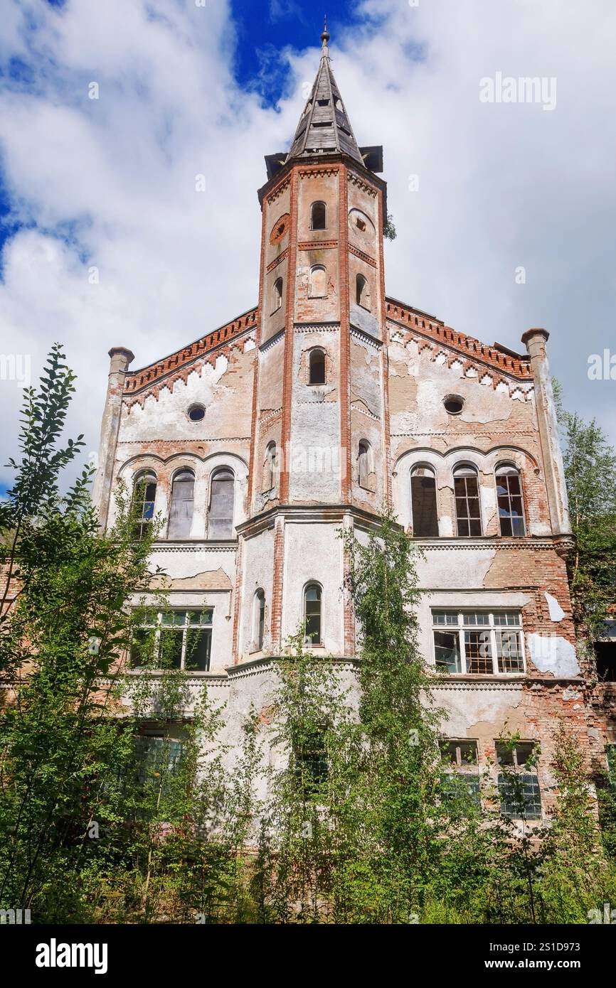 Facade of the old abandoned Catholic Church overgrown with greenery and ...