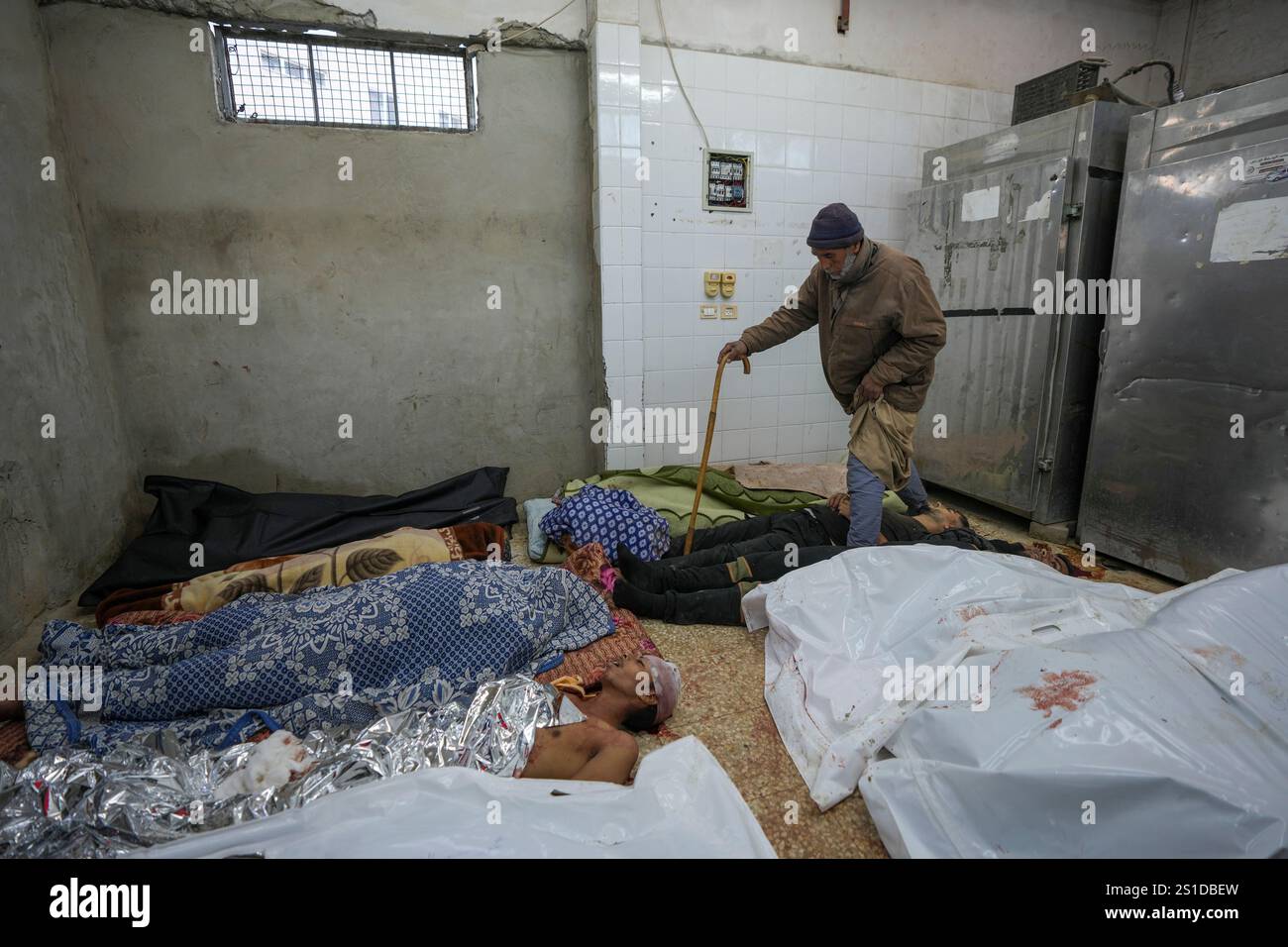 Abdallah Abu Libda walks among the bodies of victims as he searches for ...