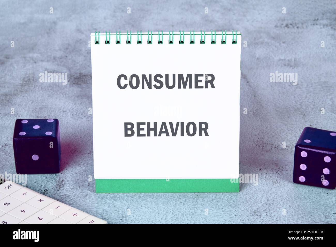 A notepad is placed on a textured surface, displaying the words consumer behavior prominently ...