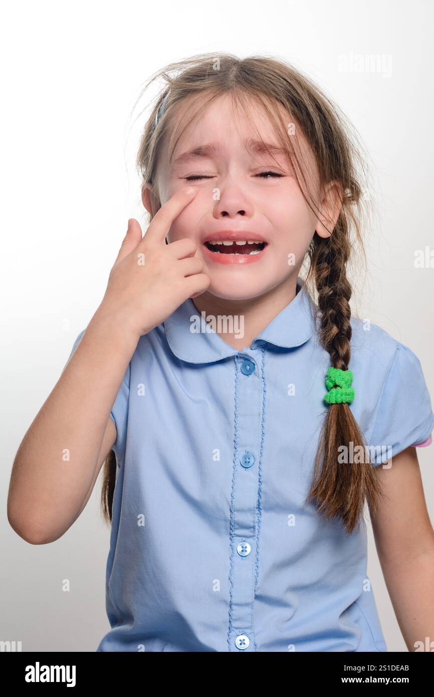 A young girl with a braid is shown crying. She's wearing a light blue ...