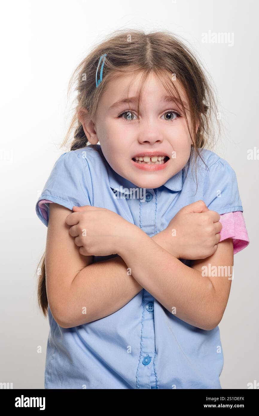 A portrait of a young girl with a worried expression, arms crossed ...